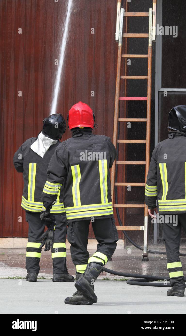 three firefighters in action with fire hydrant and ladder in the ...