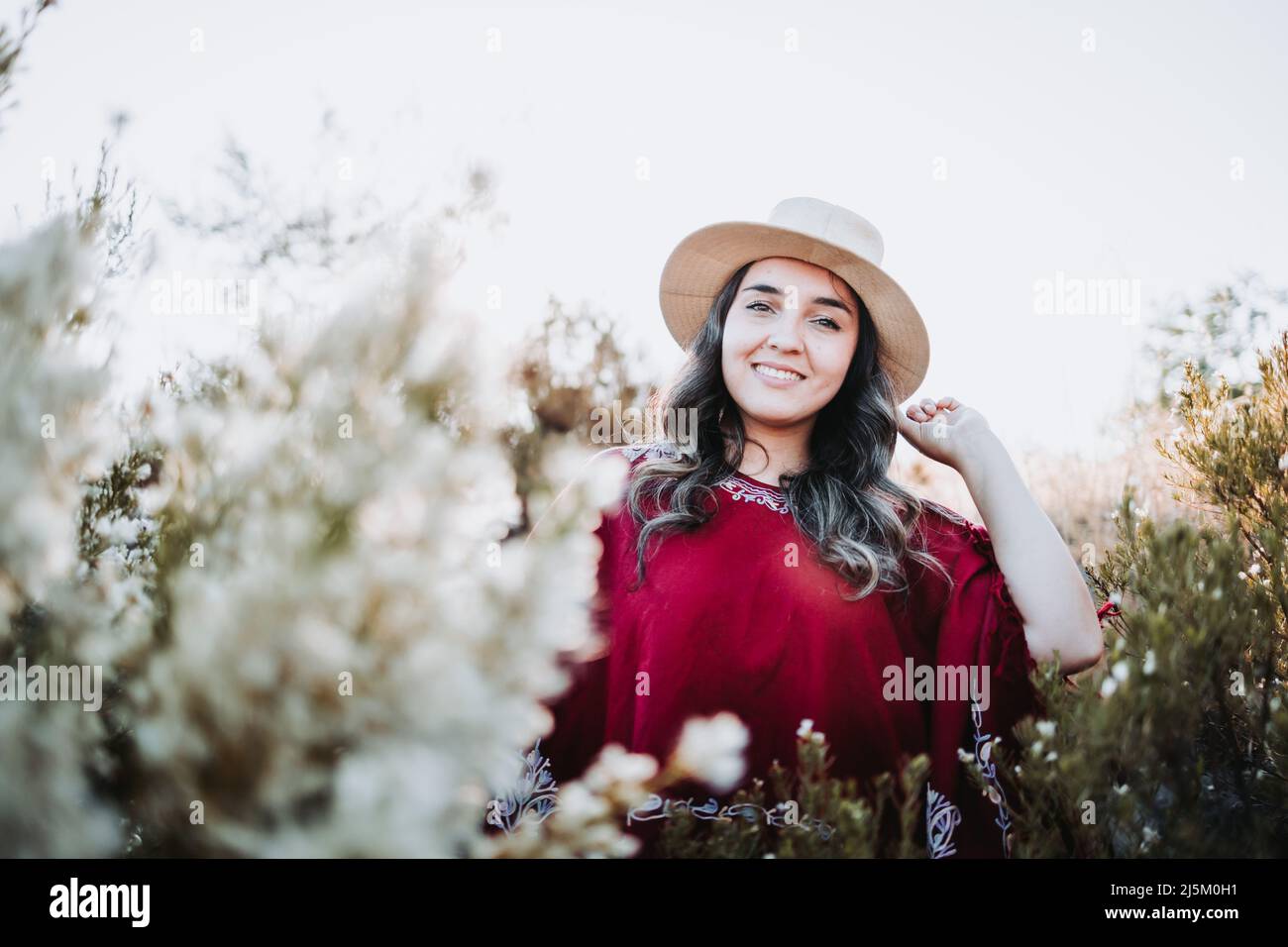 Traditional latin american woman wearing a red poncho and a hat seen ...
