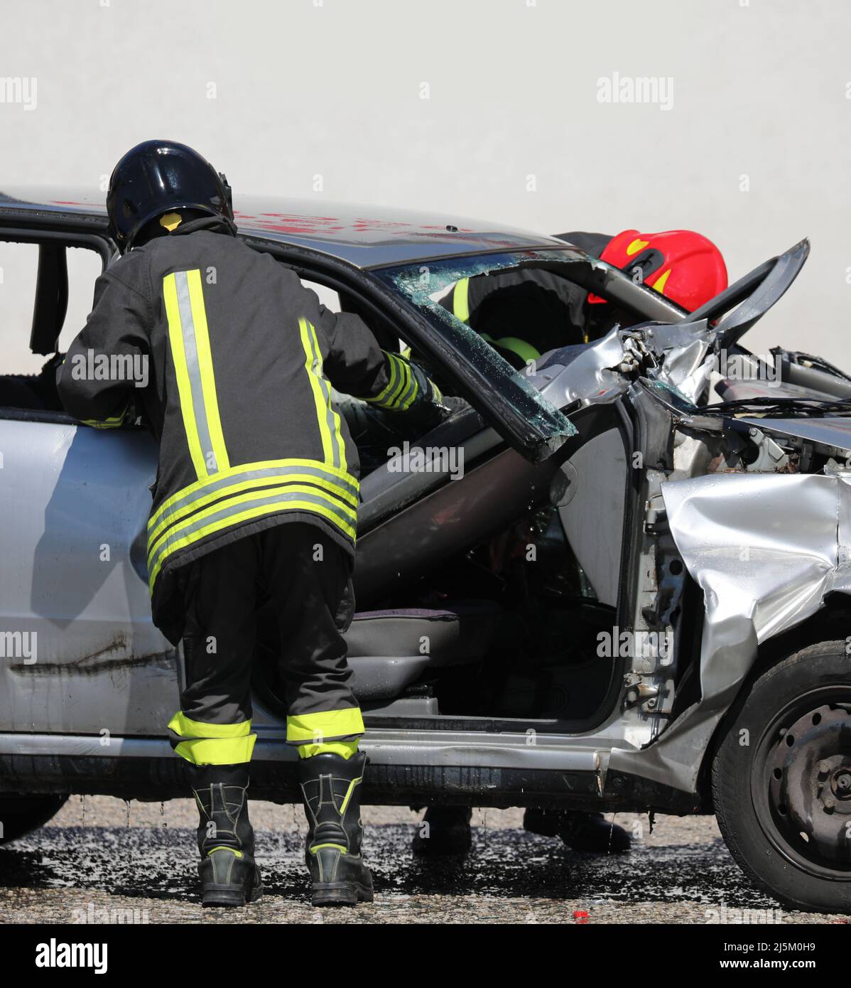 firefighters in action and the crashed car completely destroyed after ...