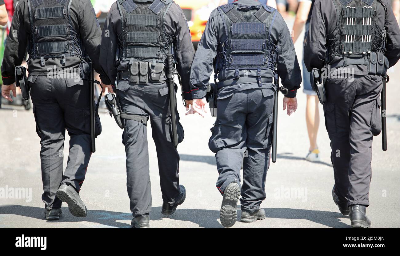 four policemen with weapons and bulletproof vests while patrolling the ...