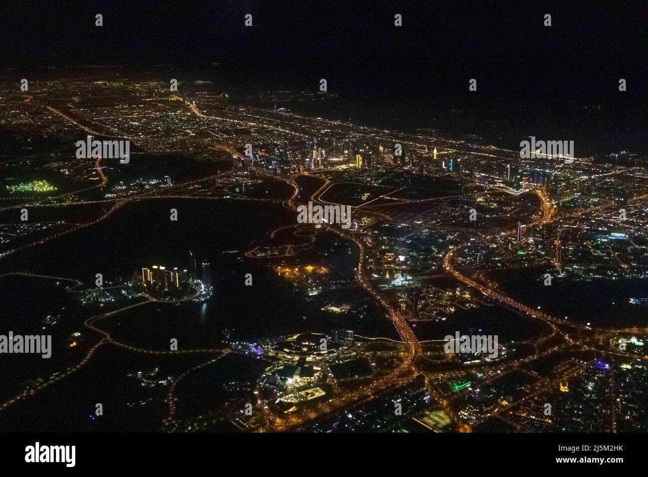 Night view of Dubai Skyline seen from flying plane above Persian Gulf ...