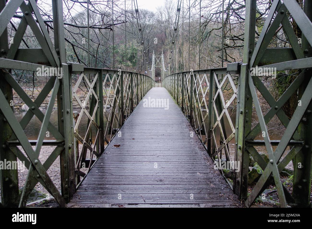 Iron suspension bridge footbridge with wood slats over the River Wharfe ...
