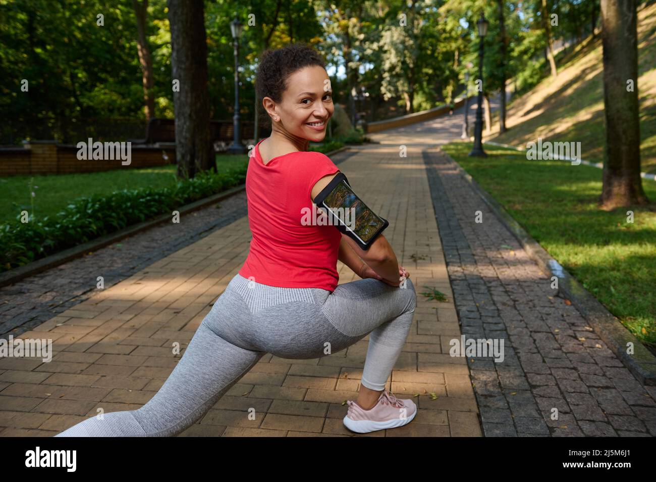 View from the back to an African woman doing lunges while exercising ...
