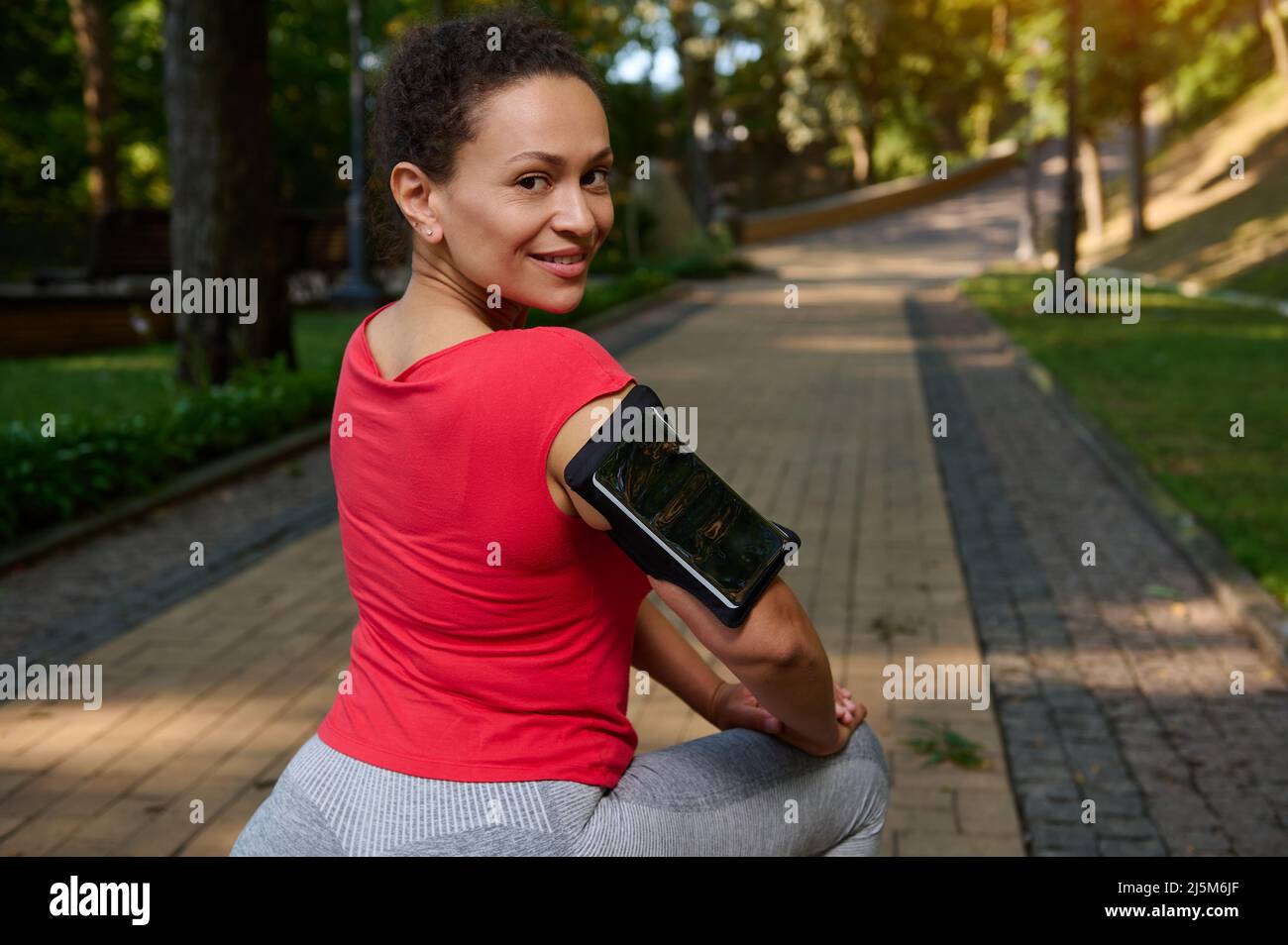 Charming middle aged fit woman in tight sportswear exercising outdoor ...