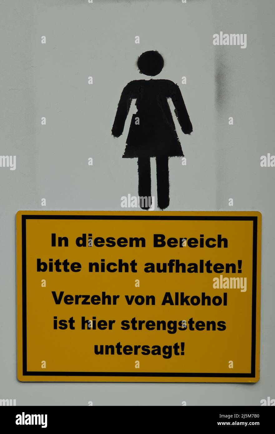 black pictogram of a woman on a toilet door and a yellow sign with ...