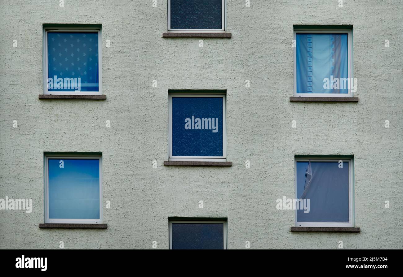 section of the white front of a building with five windows in blue ...