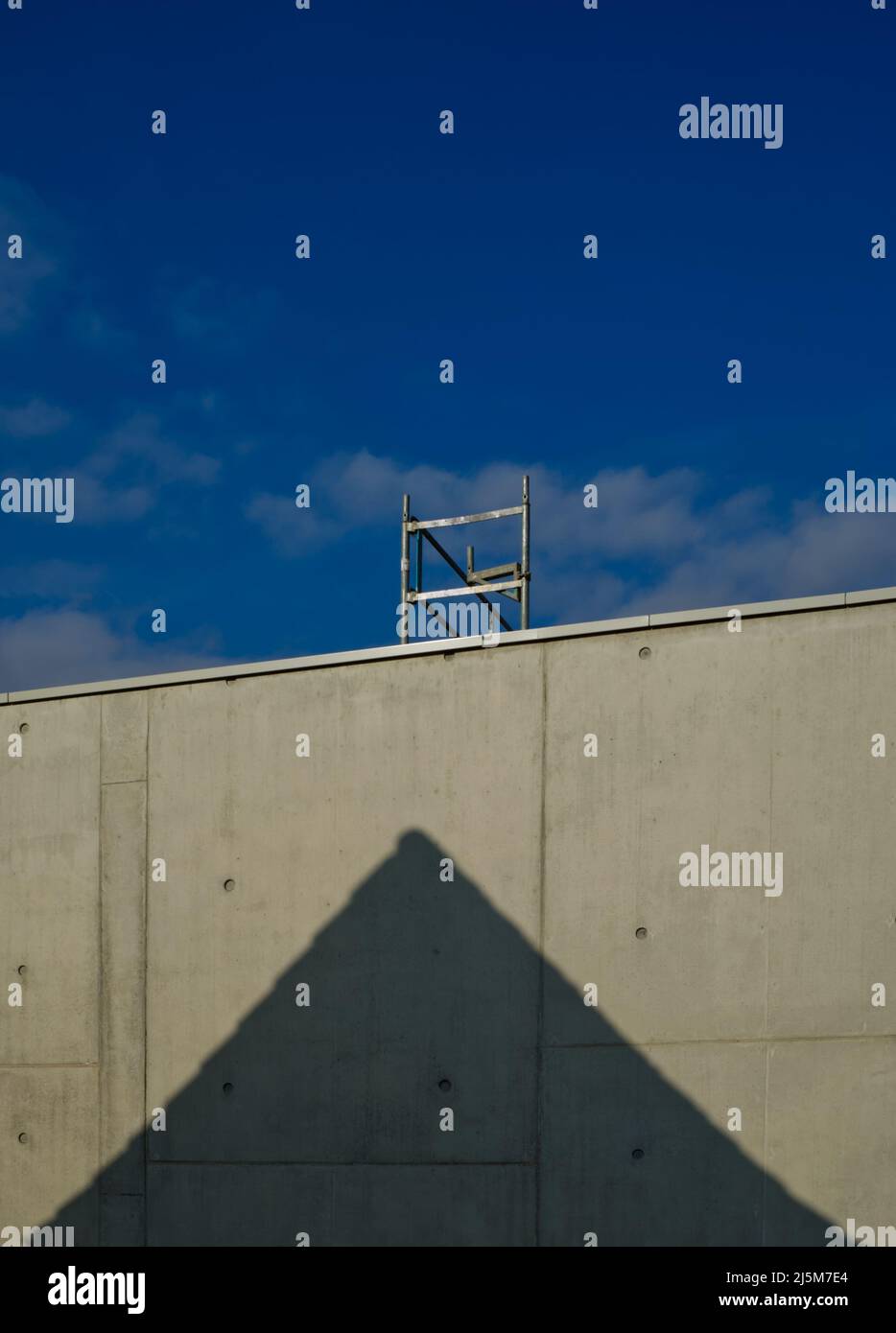 triangular shadow of a roof on a light-colored concrete wall with clear ...