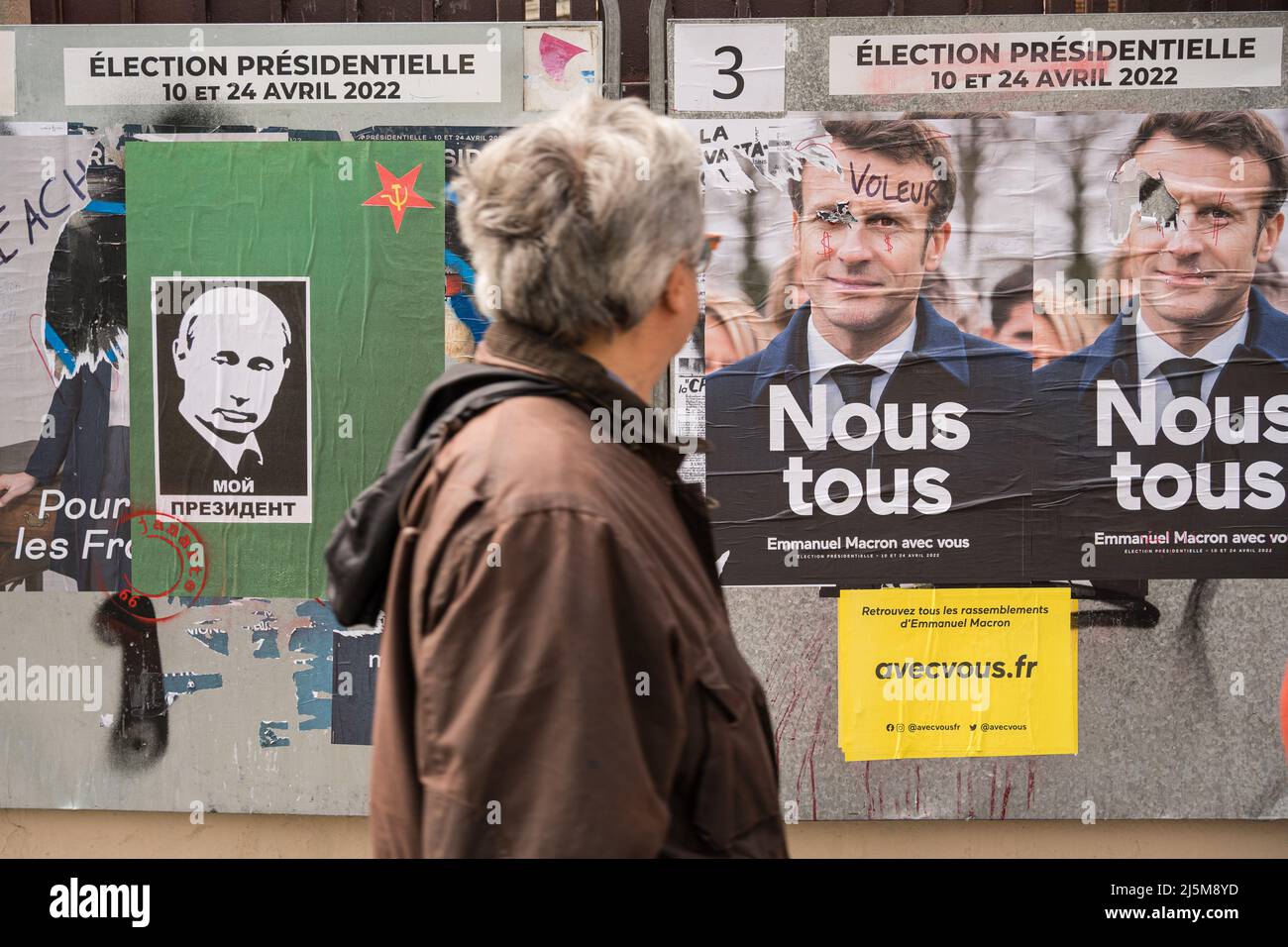 A man looks at election posters of Emmanuel Macron next to a sign of ...