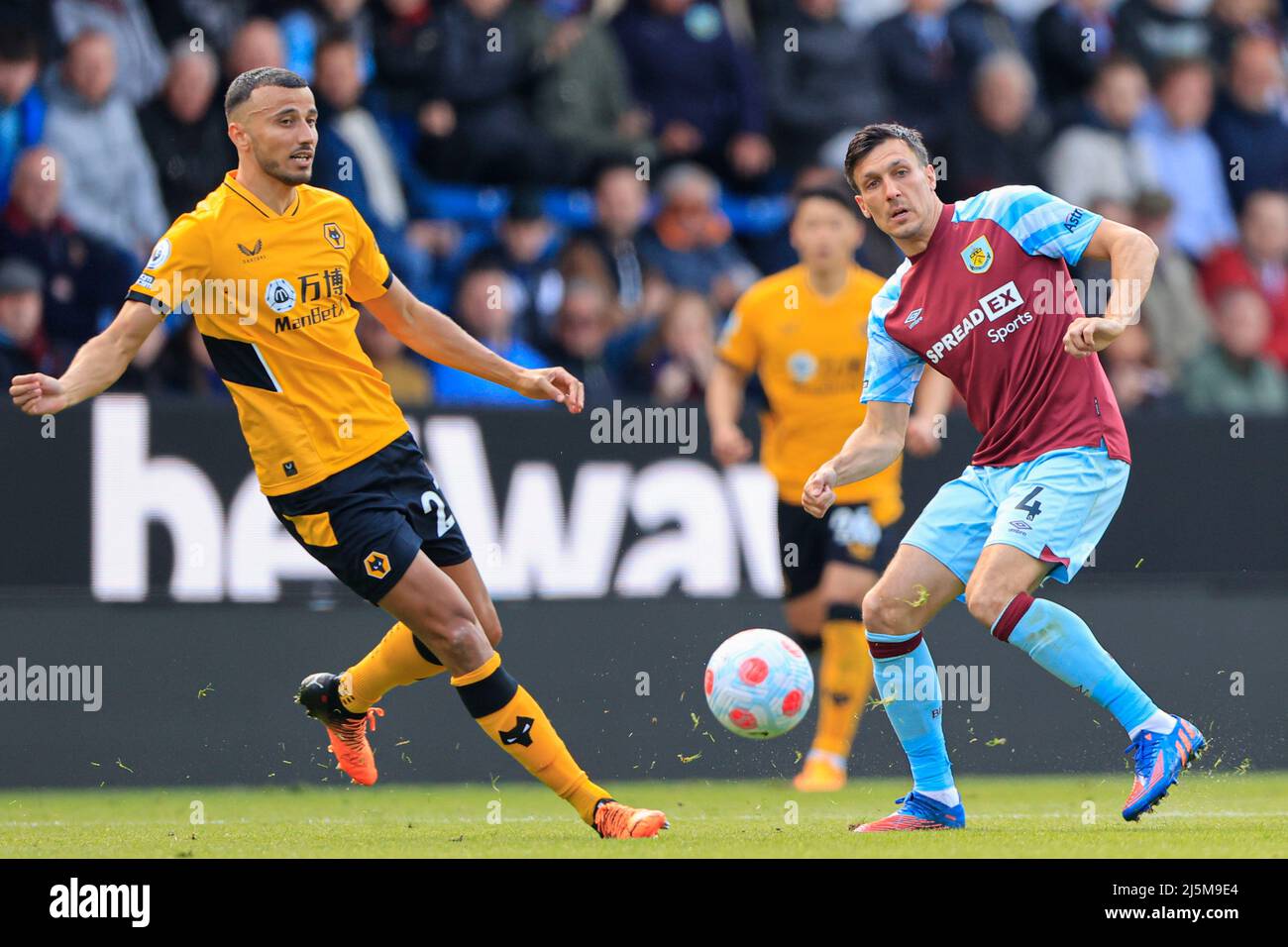 Burnley, UK. 24th Apr, 2022. Jack Cork #4 of Burnley passes the ball watched by Romain Saiss #27 ...