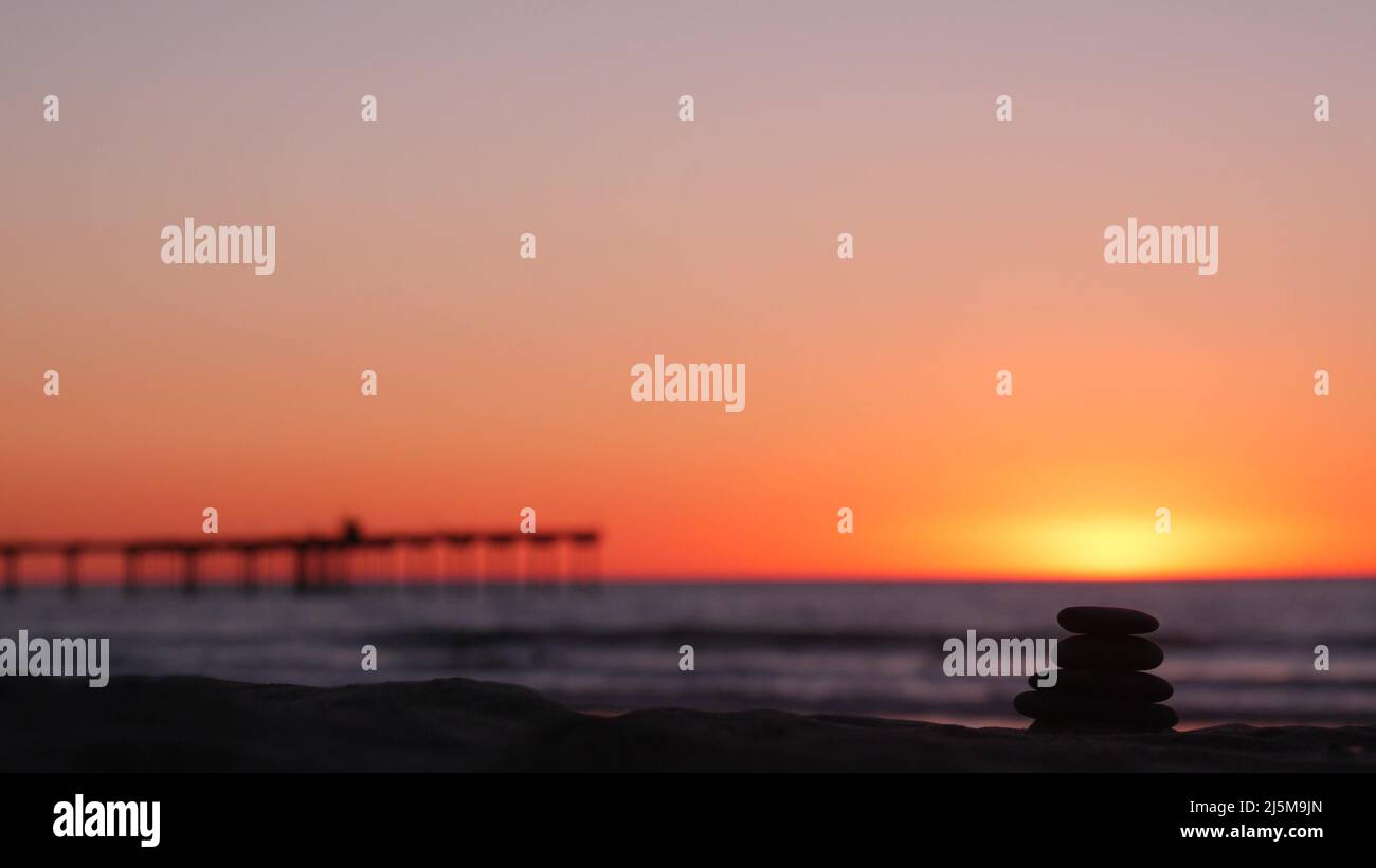 Stack of pebble stones, sandy ocean beach, sunset sky. Rock balancing ...
