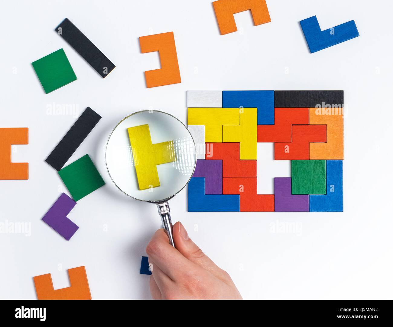 Hand with magnifying glass over suitable puzzle piece. Better way of ...