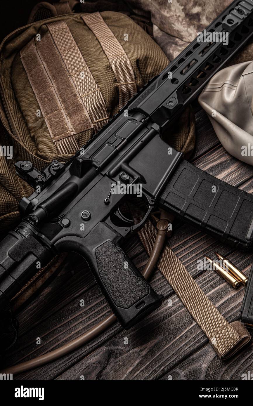 Modern automatic carbine and cartridges for it on a wooden background ...