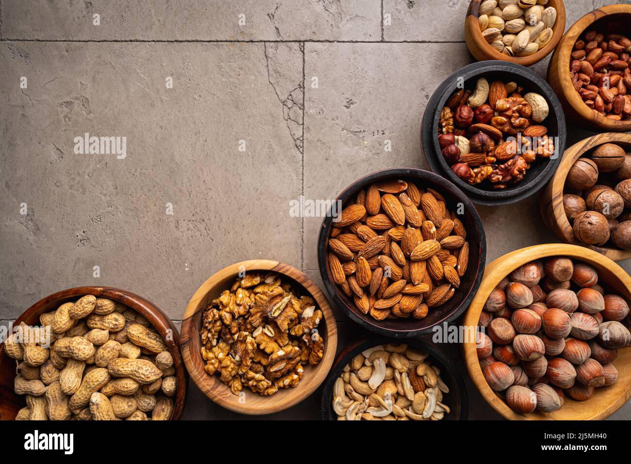 Assortment of nuts in bowls on stone background top view with copy ...