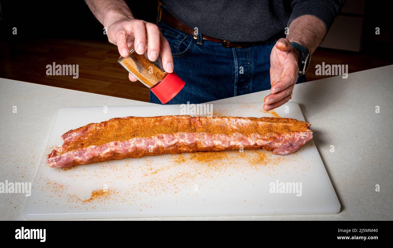Pitmaster prepares Baby Back Ribs for smoking by applying rub Stock ...