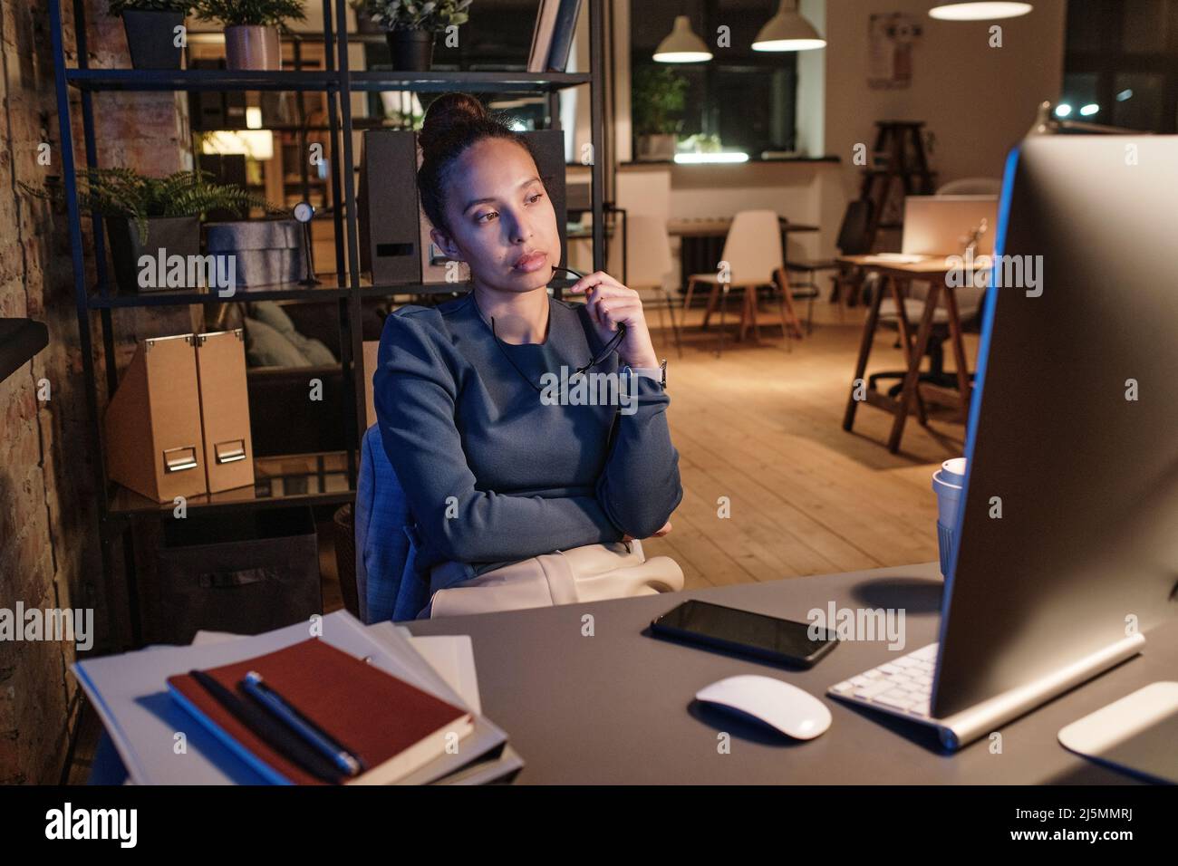 Thoughtful young mixed race project manager holding eyeglasses and ...
