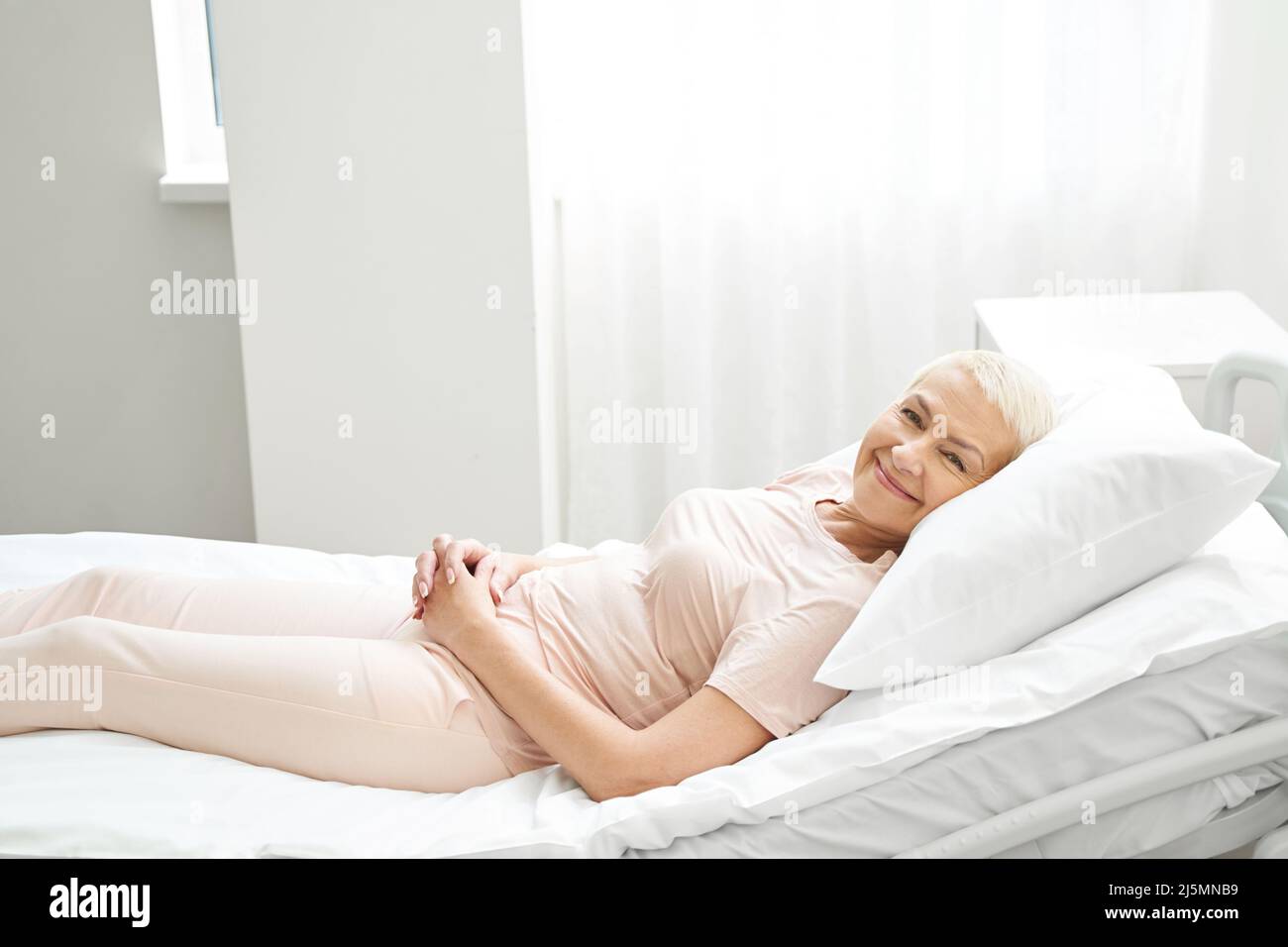 Elderly person lying in bed in medical center Stock Photo - Alamy