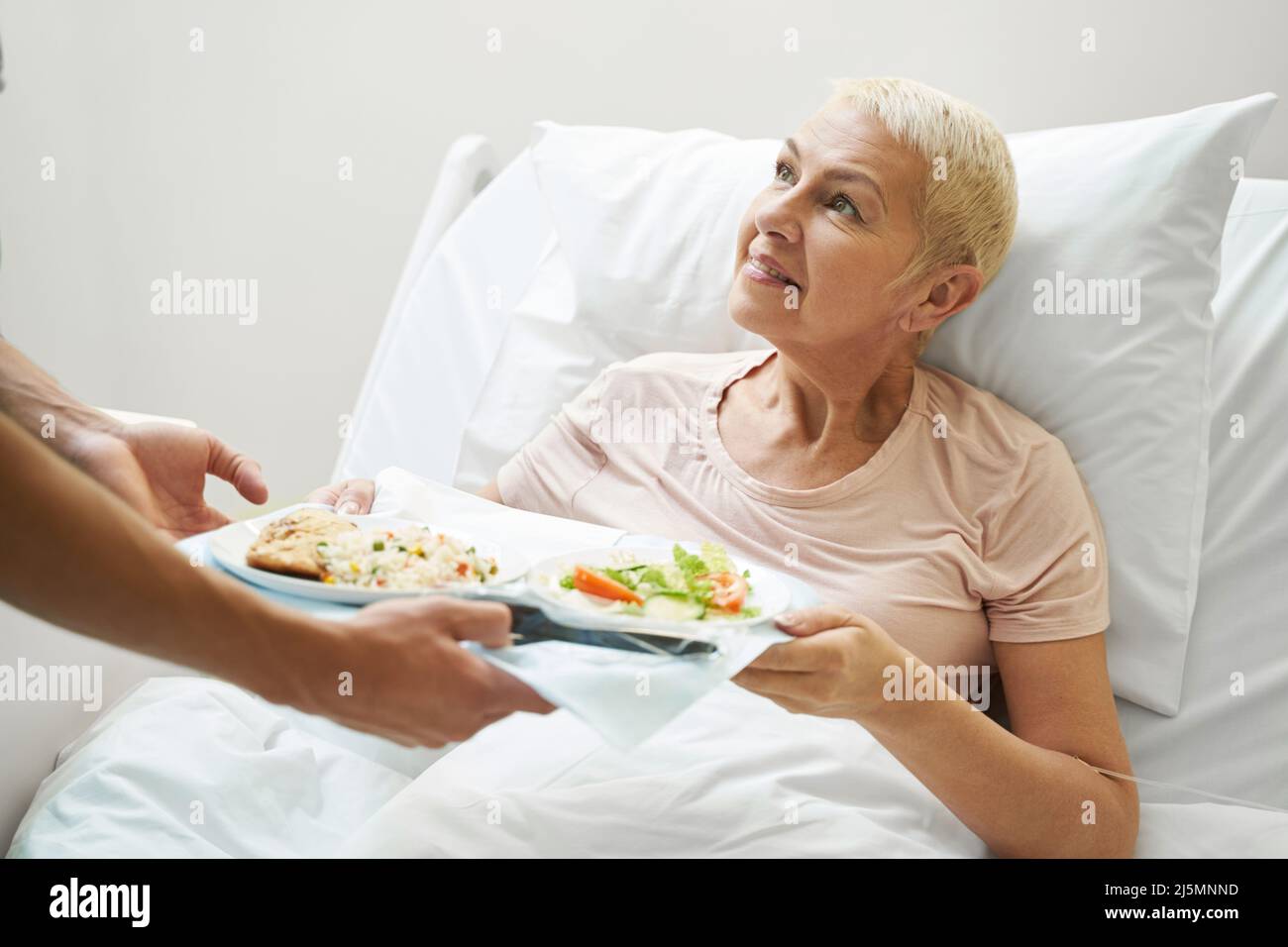 Aging lady getting meal tray from hospital employee Stock Photo - Alamy