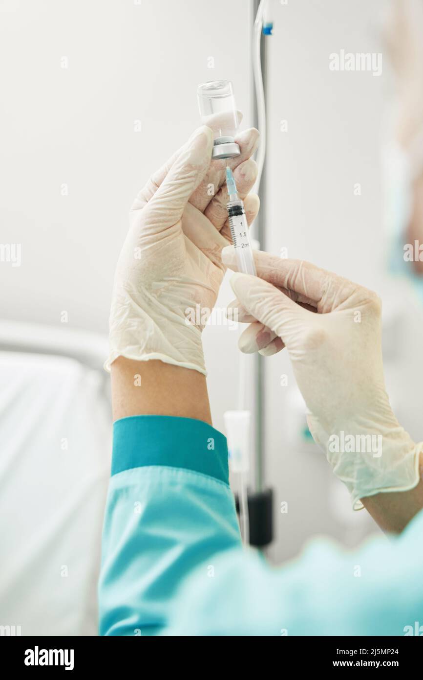Medic drawing out drug from vial into syringe Stock Photo - Alamy