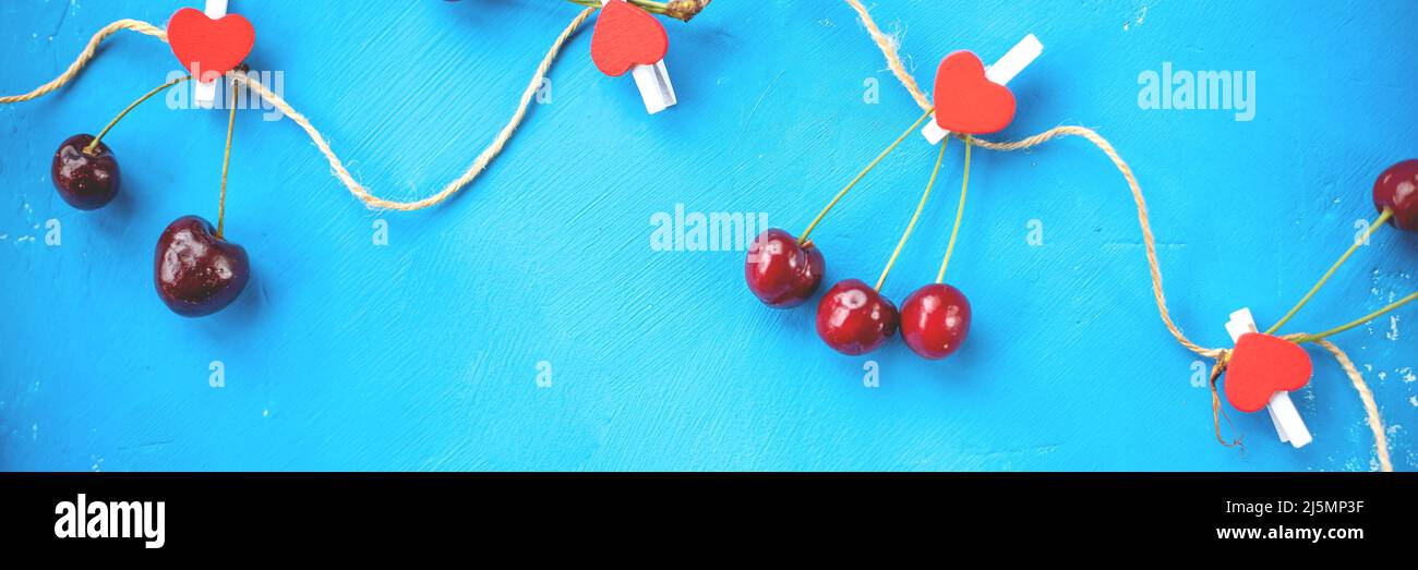 Red berries of ripe cherries hang on a rope. Concept on the topic of ...