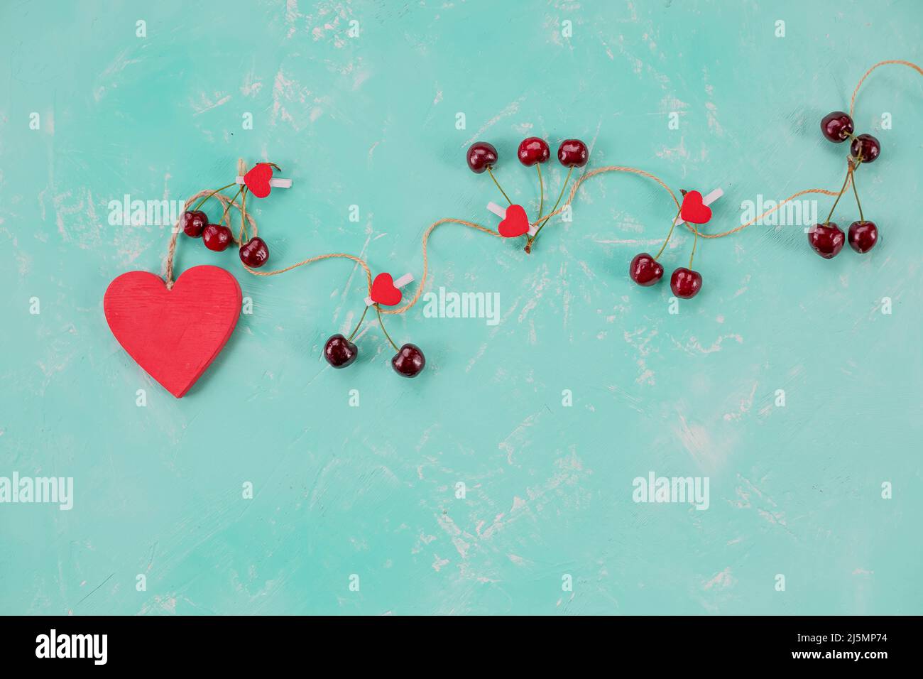 Red berries of ripe cherries hang on a rope. Concept on the topic of ...