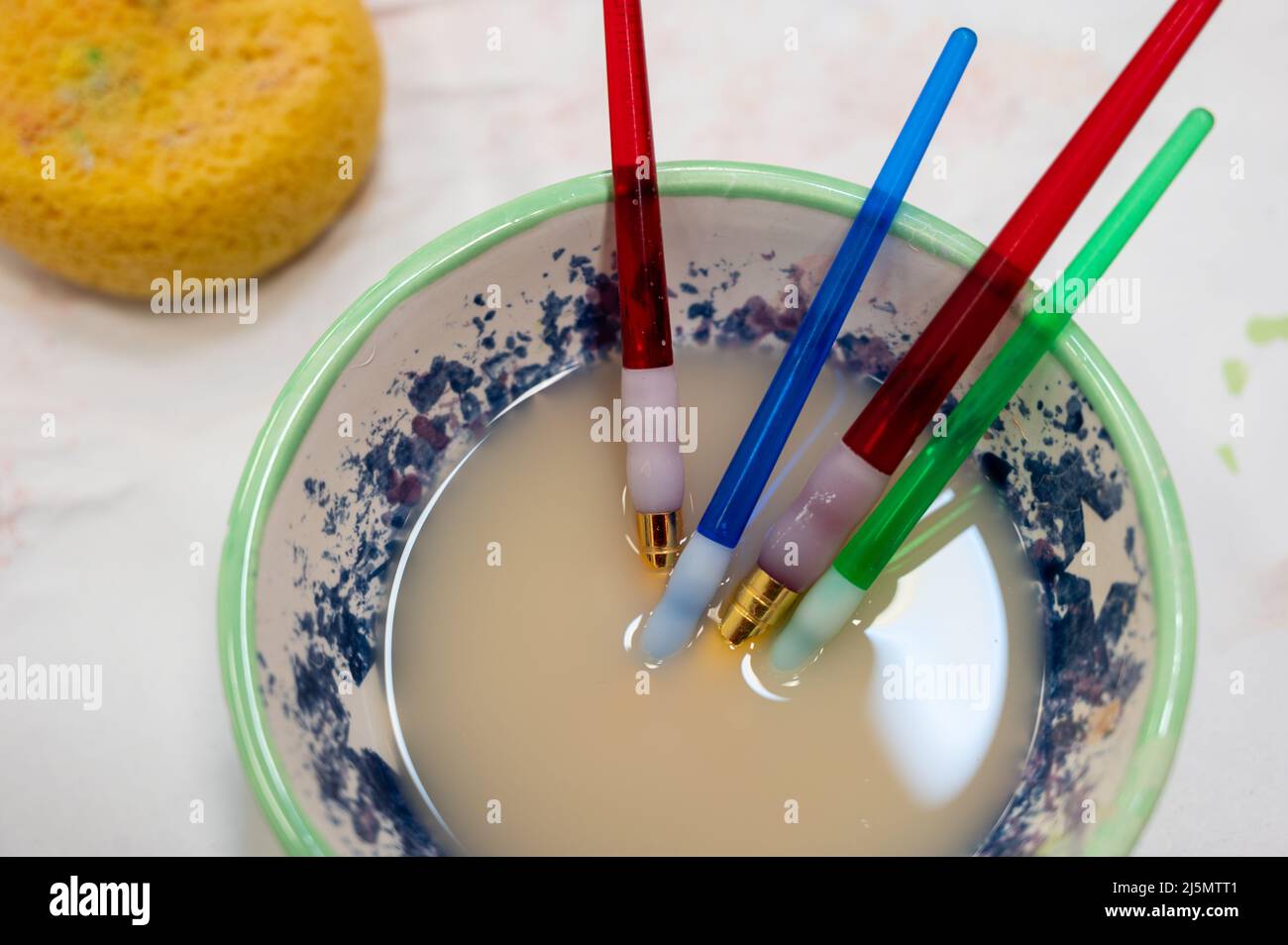 Selection of paint brushes in a bowl of dirty water from an art project ...