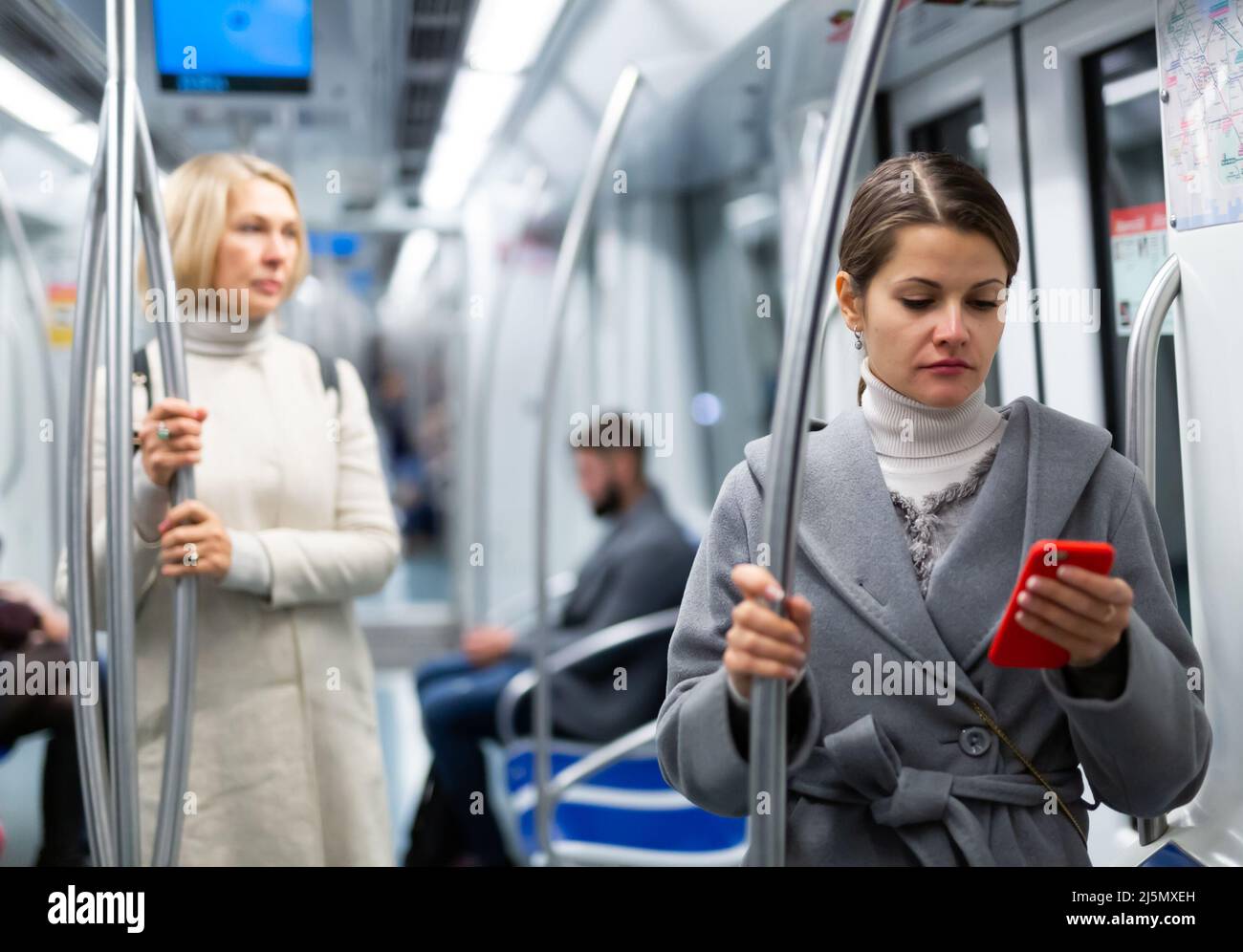 Positive woman reading from mobile phone screen in metro Stock Photo ...