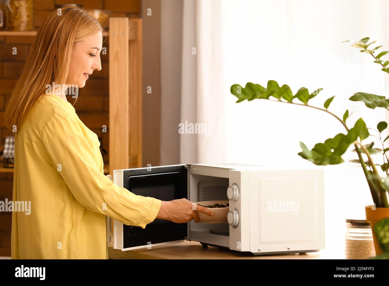 Mature woman heating food in microwave oven Stock Photo - Alamy
