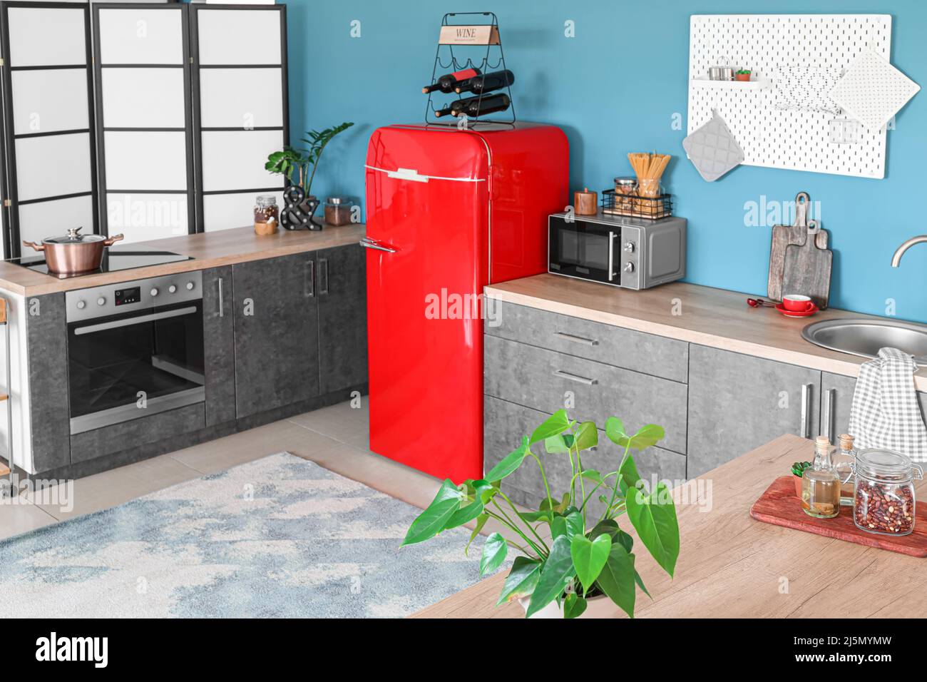 Interior of stylish kitchen with red fridge, counters and pegboard ...