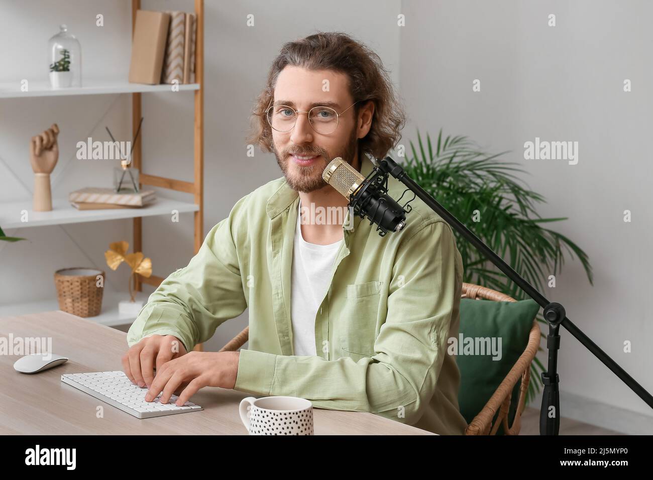 Male blogger using computer and microphone at home Stock Photo - Alamy