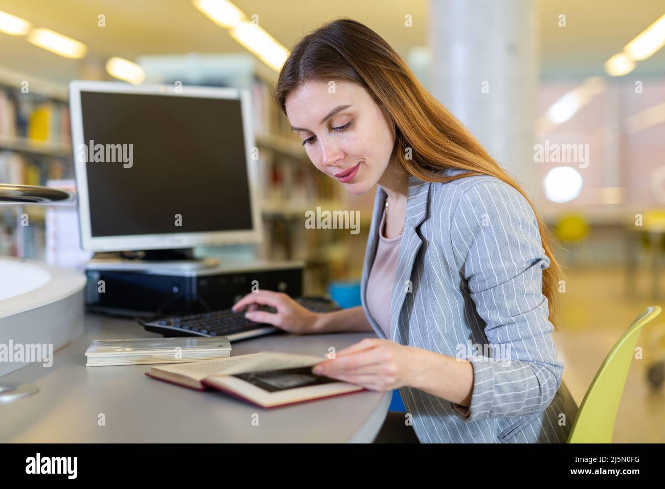 Female student with laptop and books in public library Stock Photo - Alamy