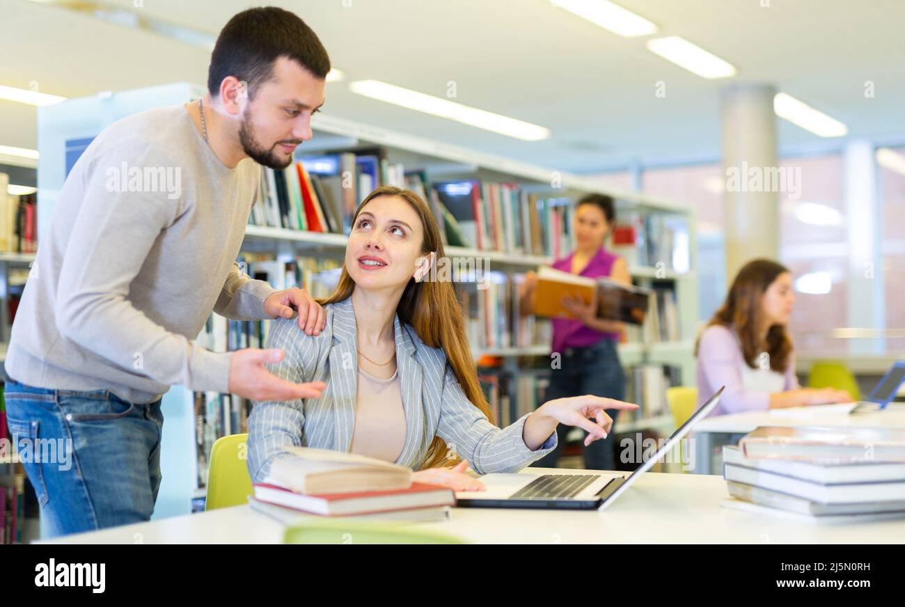 Male librarian helping focused adult student preparing to exam Stock ...