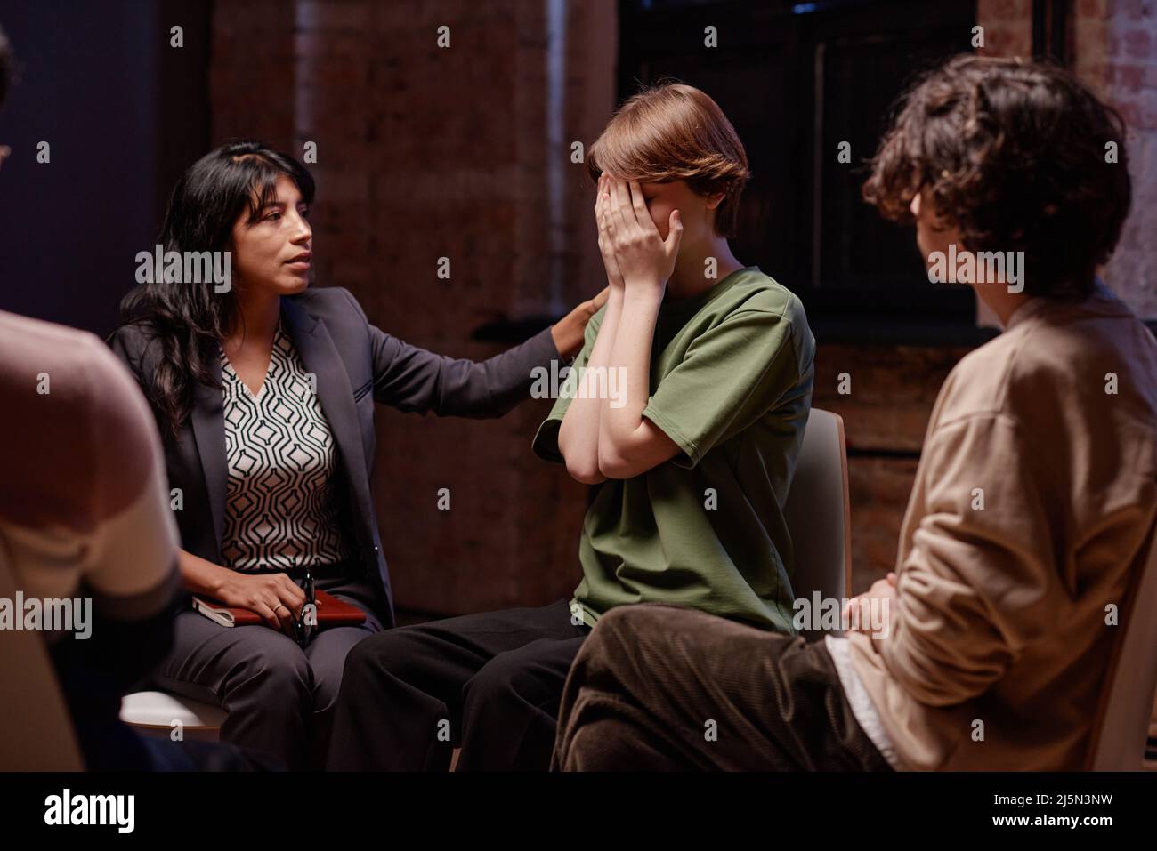 Horizontal shot of professional psychotherapist comforting woman crying ...