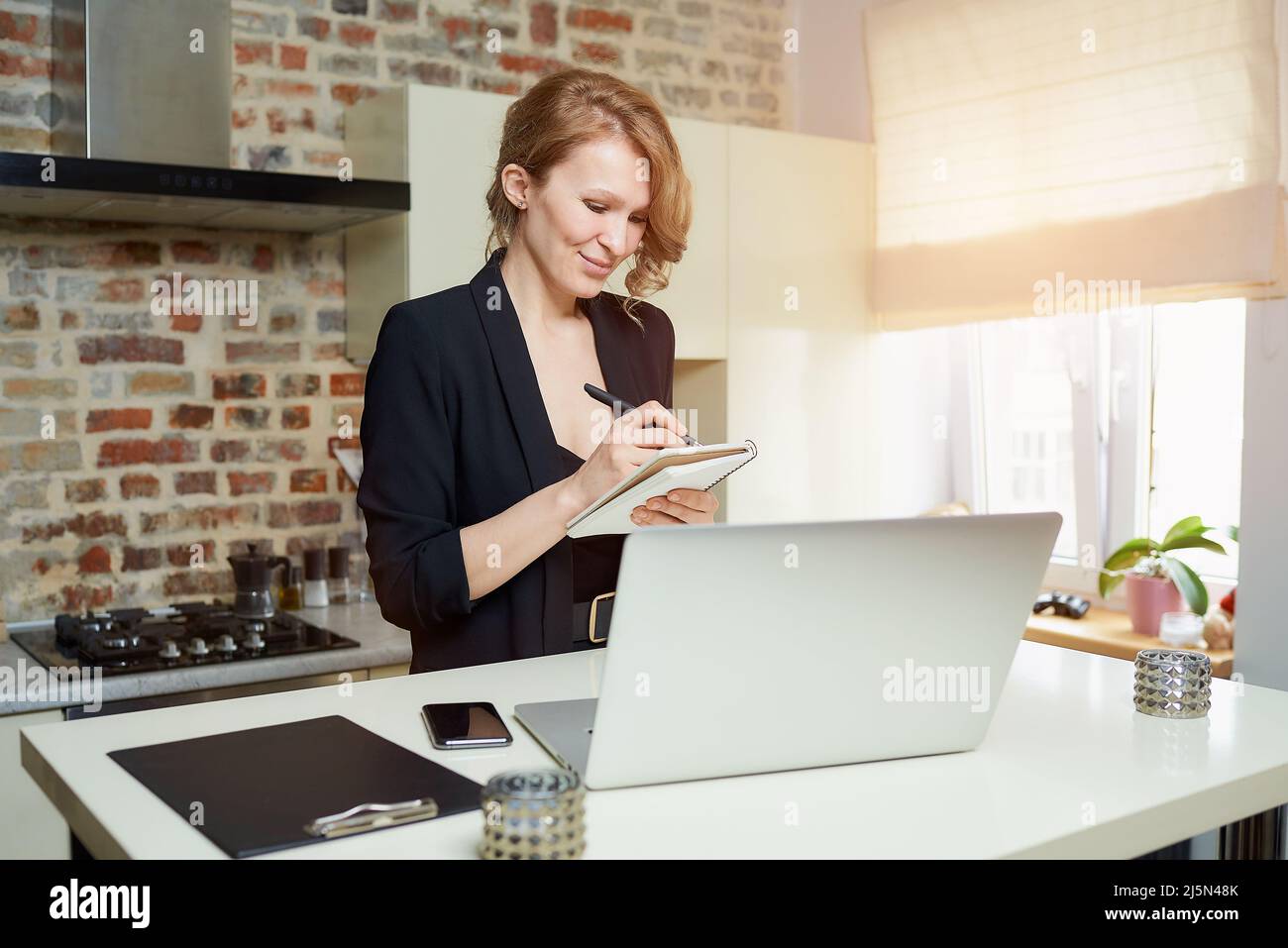 A woman doing notes during the report of a colleague at a video ...