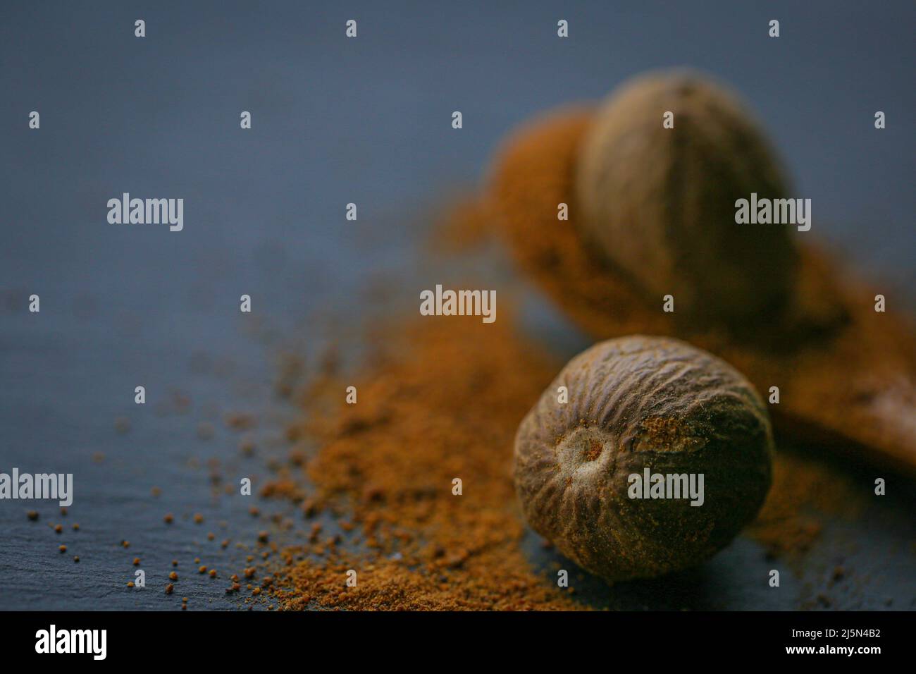 Nutmeg in a cut and nutmeg powder in a spoon on a black slate ...