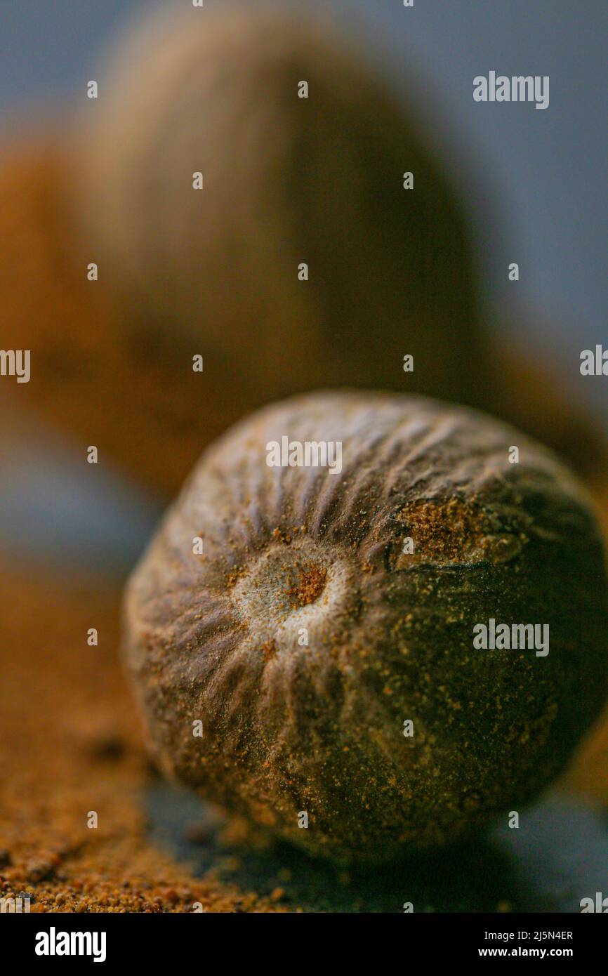 Nutmeg in a cut and nutmeg powder in a spoon on a black background ...
