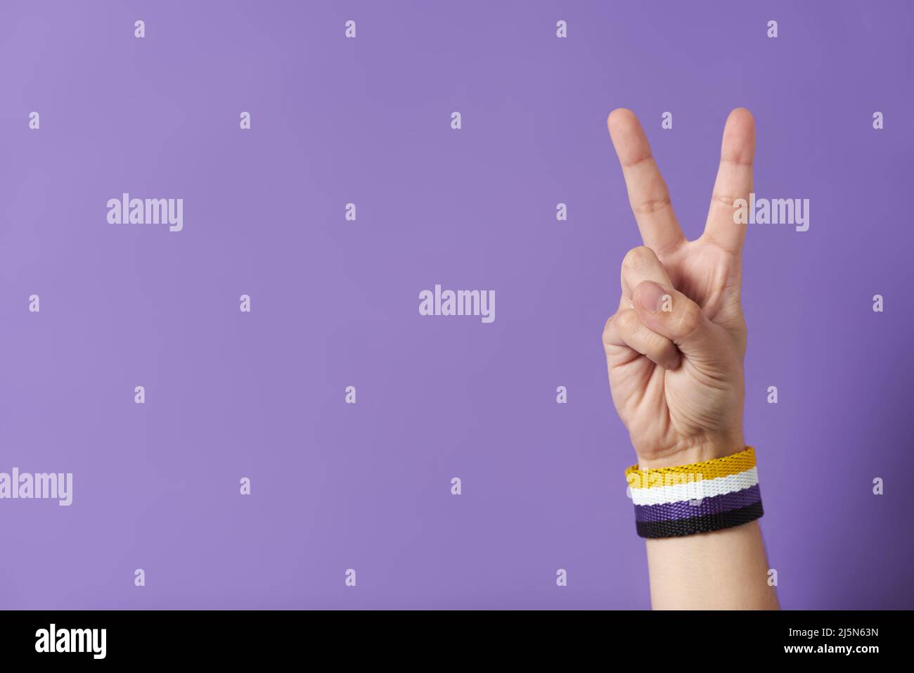 Hand making the victory or peace sign wearing a non binary flag ...