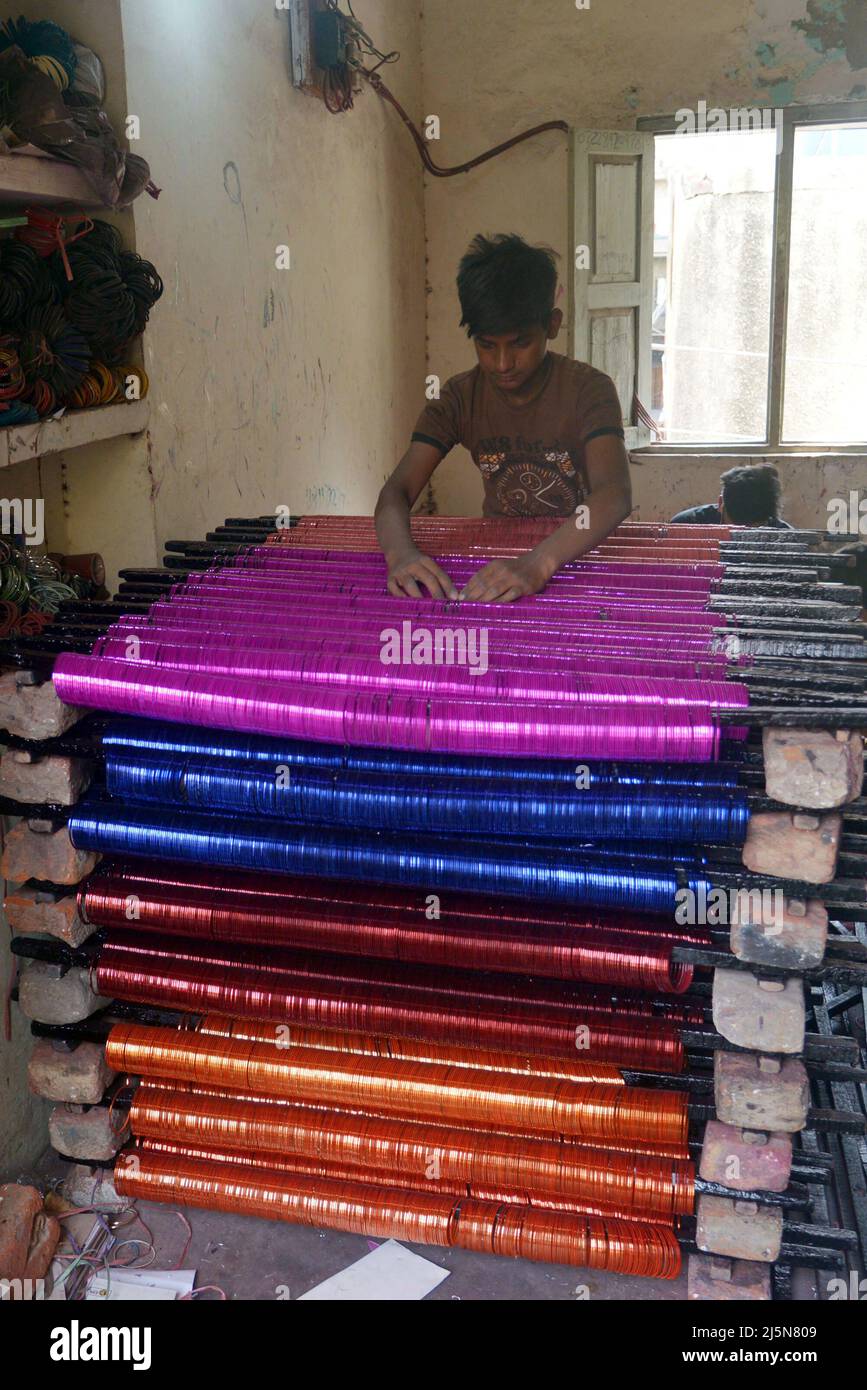 Pakistani workers are busy preparing metal bangles in a local factory ...