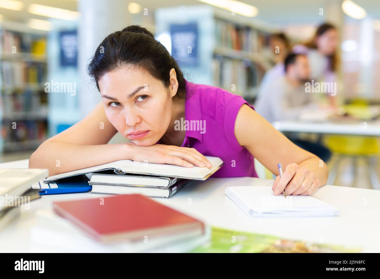 Woman resting her head on stack of books in public library Stock Photo ...