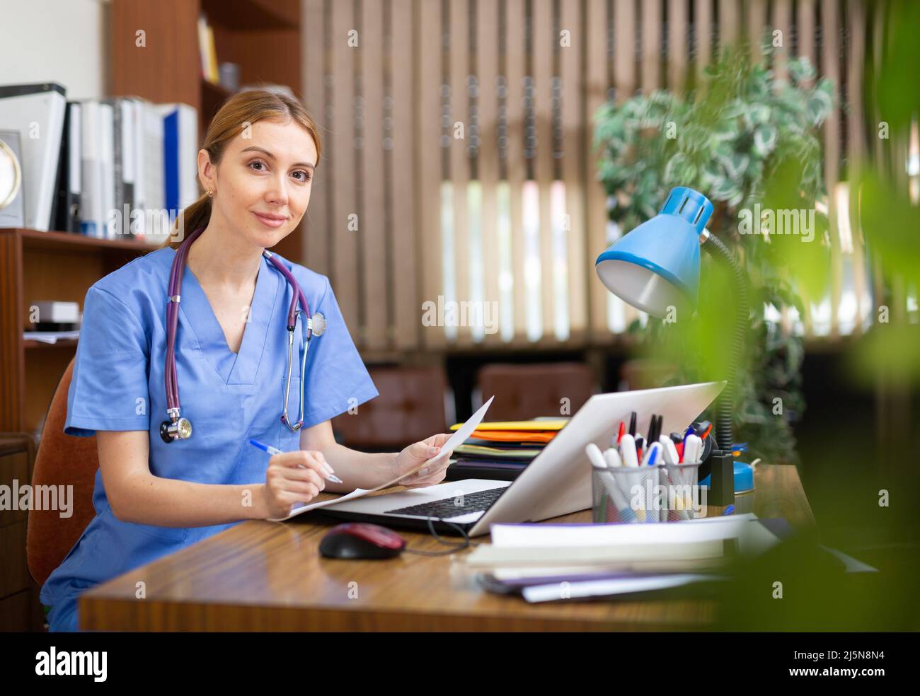 Young female general practitioner studies the patient's outpatient card ...