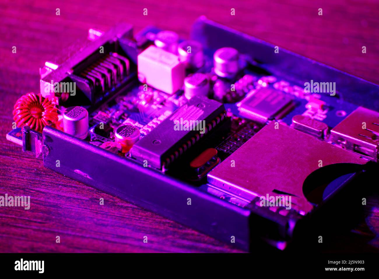 Small neon PCB with chip, ports, capacitors and connections. IT and ...