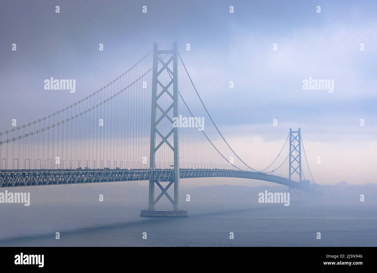 Suspension bridge in dark clouds and fog with hint of sunset Stock ...