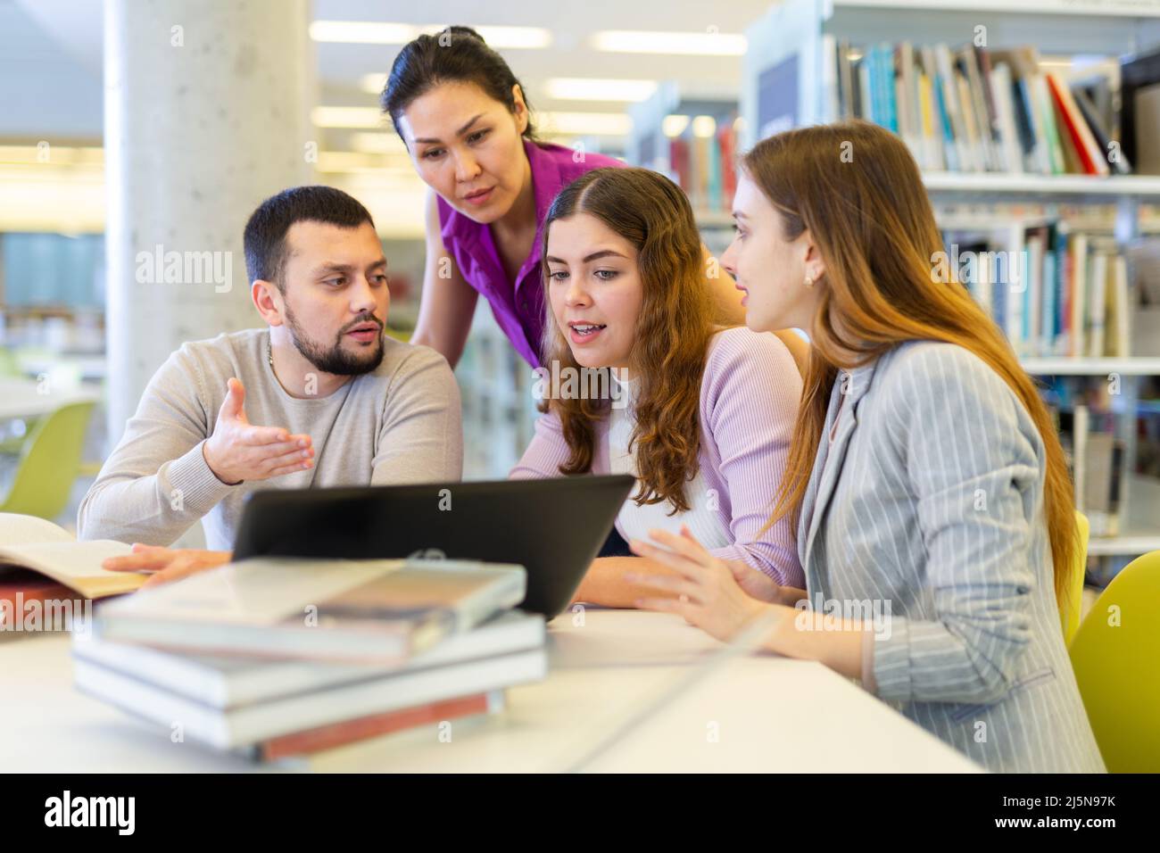 Group of students learning together at library Stock Photo - Alamy