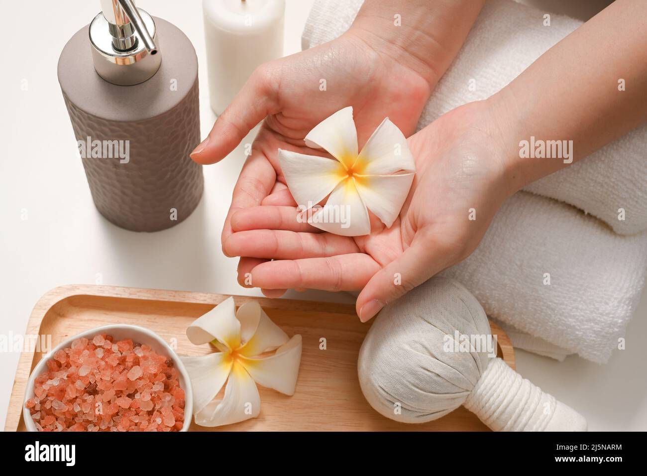 Close-up, Female hands holding a frangipani flower over luxury spa ...