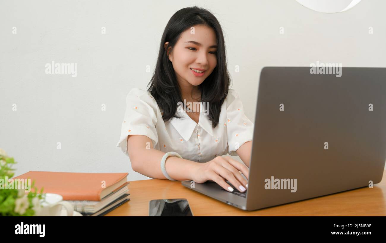 Attractive millennial Asian female college student using laptop ...