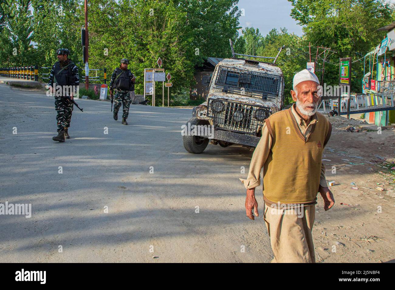 An elderly man walks past Indian paramilitary troopers standing on ...