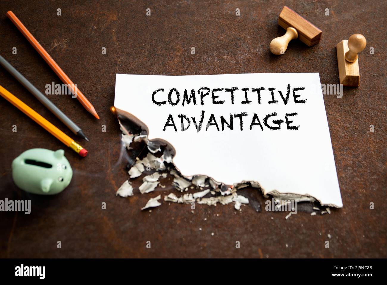 Competitive Advantage. Burning sheet of paper with text on a rusty ...