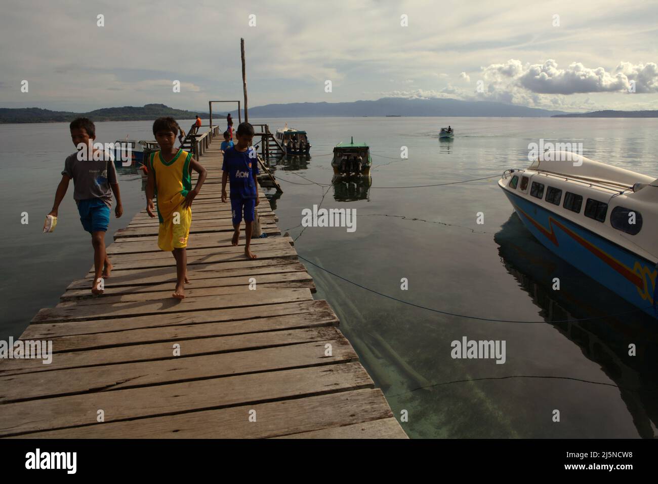 Children walking along a wooden jetty in Tulehu, Ambon Island, Central ...