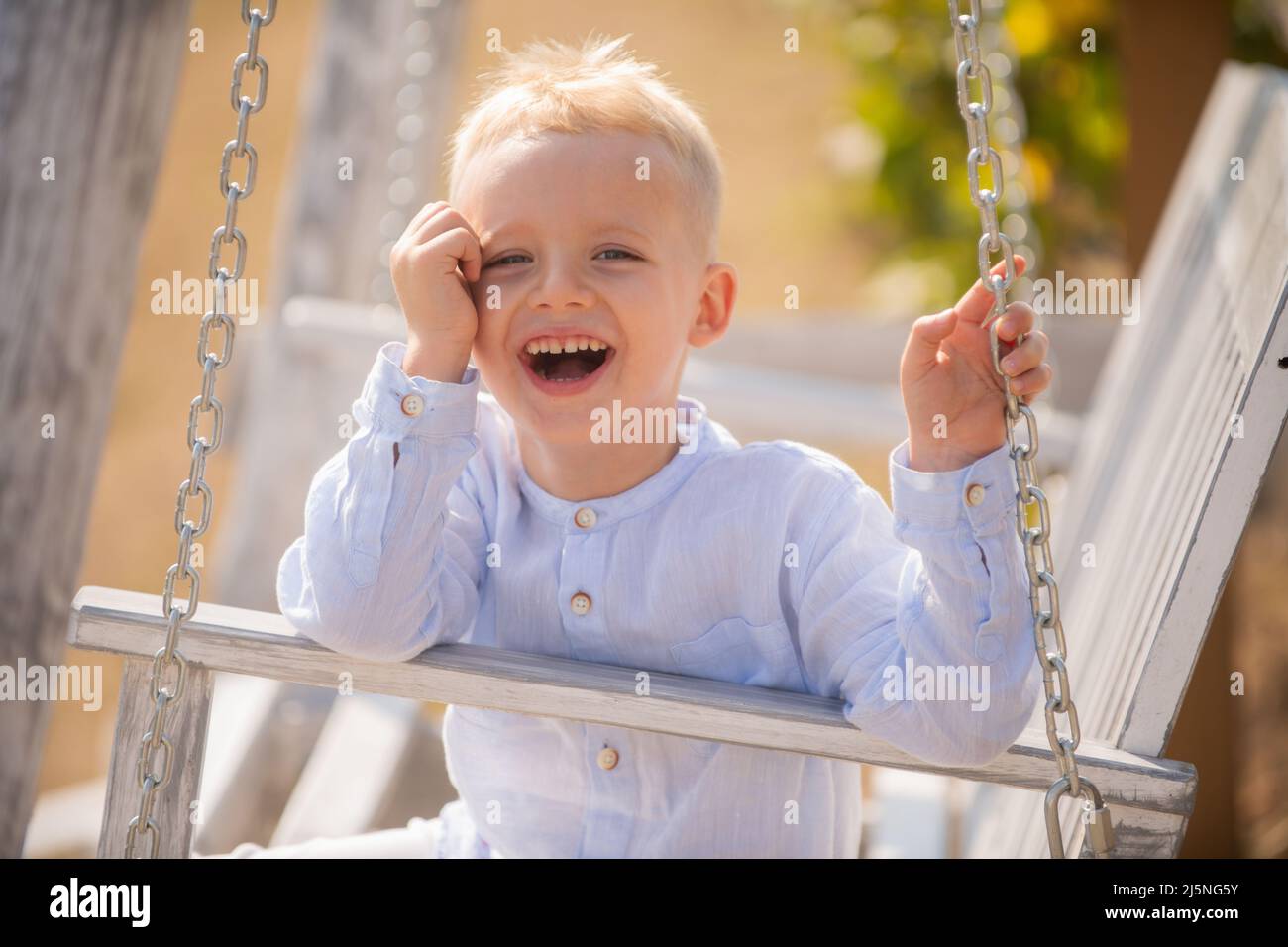 Child swing on backyard. Kid playing oudoor. Happy cute little boy ...