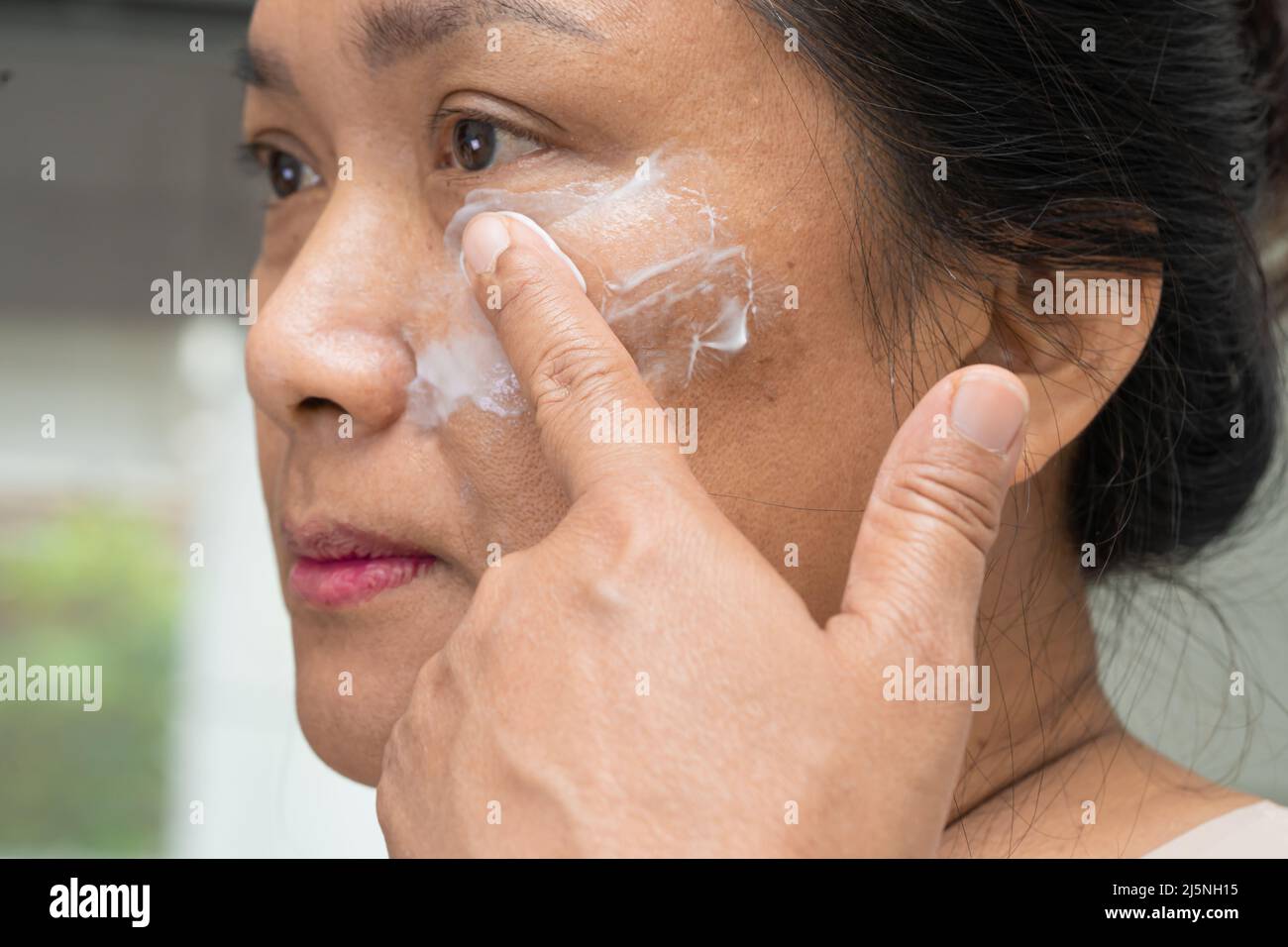 Asian lady woman applying cream skincare treatment to solve blemishes ...