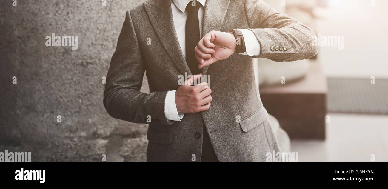businessman in classic suit is looking at his watch in city. office ...